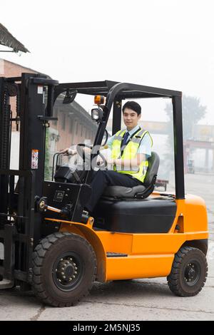 Logistics warehouse workers forklift driving Stock Photo - Alamy