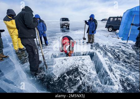 Digging a hole in the ice for scuba diving, Lake Baikal, Olkhon Island ...