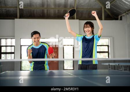 Asian ping pong doubles players excited when they score Stock Photo - Alamy