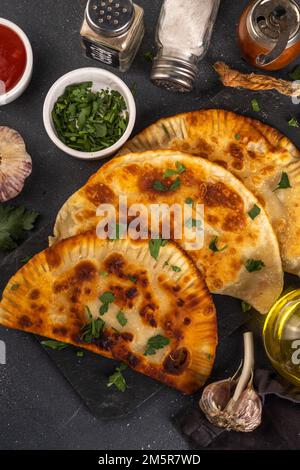 Homemade fried chebureks with meat and herbs in a pan, traditional ...