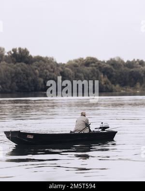 Old fisherman fishing from a wooden boardwalk at Trillium Lake with the ...