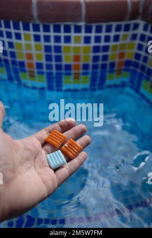 Hand holding small tile from floor of swimming pool. Tile from pool ...