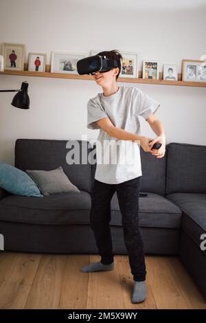 Boy having fun playing simulation games, using virtual reality headset ...