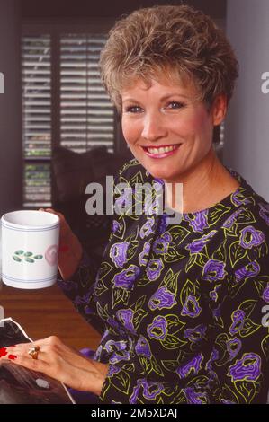 Woman holding a coffee cup smiling and looking away on a sunny day ...