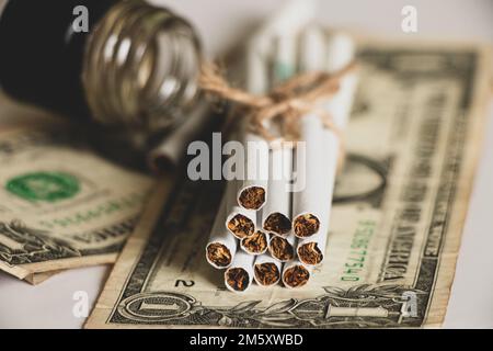 cigarettes lie on dollars and an empty bottle of alcohol on a white ...