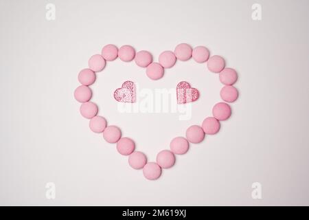 Sweets candies as heart with two glittering pink hearts on white ...