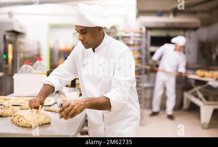 portrait of latino male baker making cookies in bakehouse Stock Photo ...