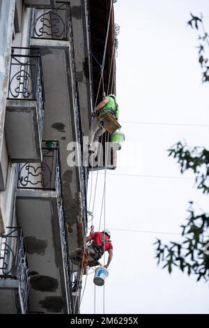 painters working on facade hanging from ropes Stock Photo - Alamy