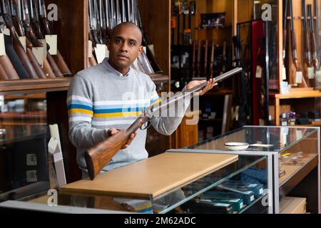 Hispanic salesman showing collectible rifled musket in gun store Stock ...