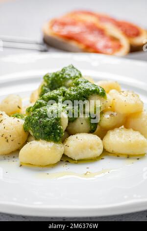 Appetizing gnocchi with pesto sauce served on white plate with toasts ...