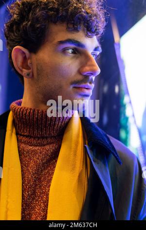 Pondering ethnic guy with curly hair in round glasses looking out ...