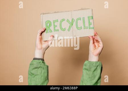 Unrecognizable kid raising arms with carton Recycle placard during ...