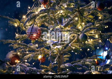 Christmas tree bulbs with yellow garlands covered snow, outdoor xmas ...