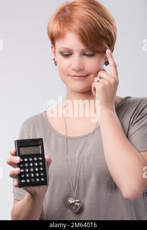 Young thinking woman is using a calculator Stock Photo - Alamy