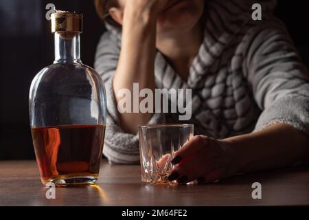 Female alcoholism. Female woman sit to table drink alcohol bottle at ...