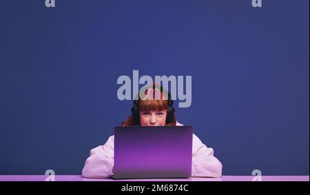 Woman with ginger hair looking at her gaming laptop thoughtfully in a ...
