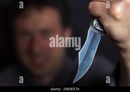 Close up of Hand with knife following young terrified man Bandit is ...