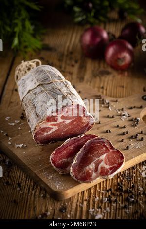 Smoked pork gammon meat slices on a wooden rustic cutting board. Dark ...