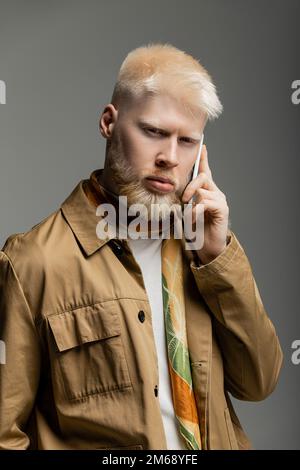 bearded albino man in shirt jacket holding smartphone with blank screen ...