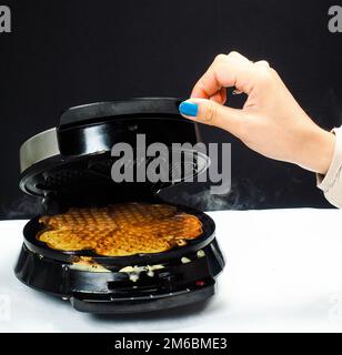Making waffles at home - waffle iron and ingredients - milk, eggs and ...