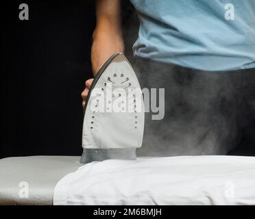 Male person using a steaming hot iron over a white shirt Stock Photo ...
