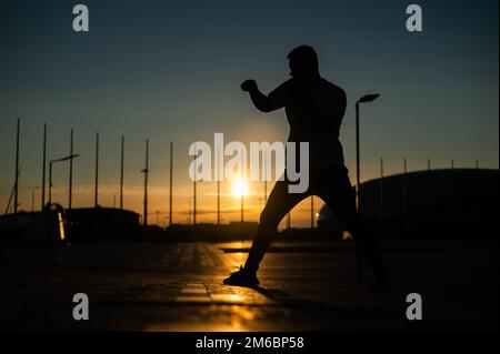 A man trains boxing at sunset outdoors Stock Photo - Alamy
