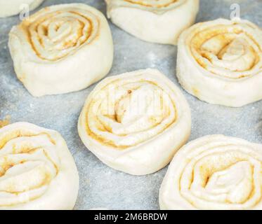 Closeup of raw cinnamon roll and cinnamon buns on baking paper Stock ...