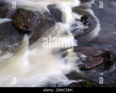 Strong current in river passing rocks, long exposure Stock Photo - Alamy