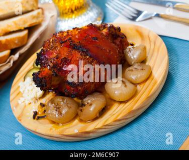 Appetizing pork knuckle served with boiled onions and pickled cucumbers ...