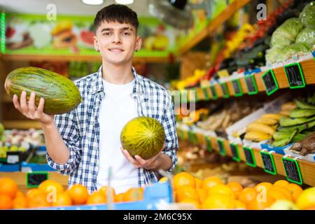 Serious European male picking ripe organic avocados in plastic ...