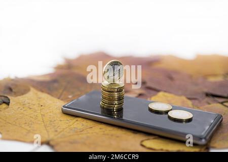 Smartphone on maple leaves background with some coins. Autumn ...