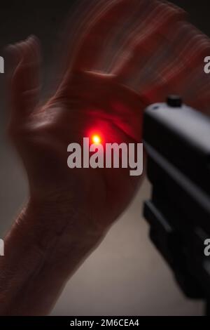 Expressive hands in front of a pistol with a laser gunsight Stock Photo ...