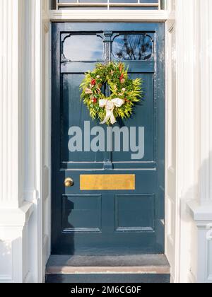 Gold and white front door decorated with Christmas decorations and snow ...