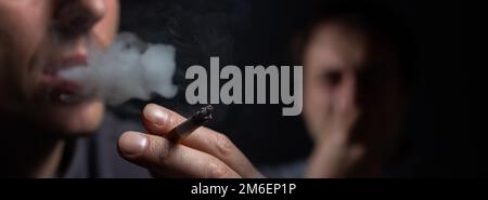 Passive smoking concept. Man is smoking cigarette and man is covering ...
