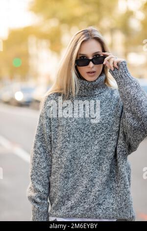 Woman adjusting sunglasses with modern city skyline and river in the ...
