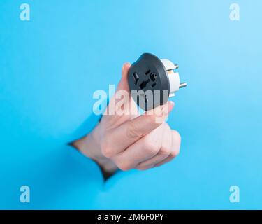 A woman's hand sticks out through a blue paper background and holds a ...
