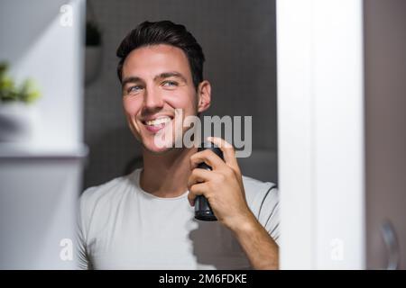 Man using deodorant while looking himself in the mirror Stock Photo - Alamy