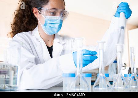 Left handed woman scientist analyzing solutions with blue gloves and ...