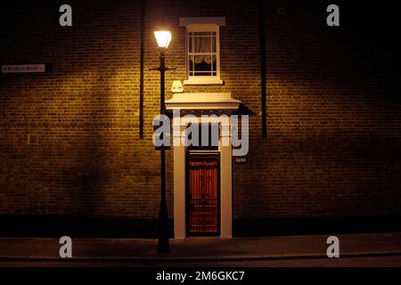 A dark ominous London door way at night lit by a single street light ...