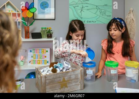 Student recycling cardboard on selective trash bin in ecology classroom ...