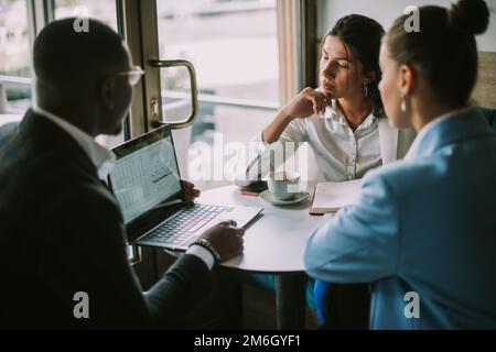 Three bussinesspeople looking at statistics and charts for their recent ...