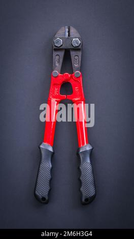 Aerial view of a red steel cutter with rubber handle on a black ...