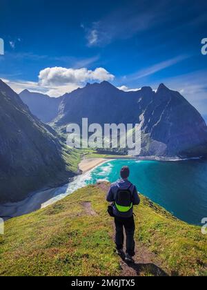 Adventurer hiking on mount Ryten with view over the Kvalvika Beach ...