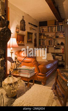 Brown leather sofa in reading room decorated with paintings, swords ...