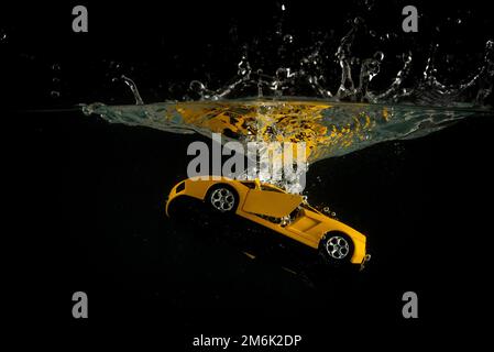 Yellow miniature toy car dropped splashing and sinking on water Stock ...