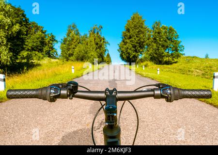 First person view of handling the bicycle on the empty asphalt road ...