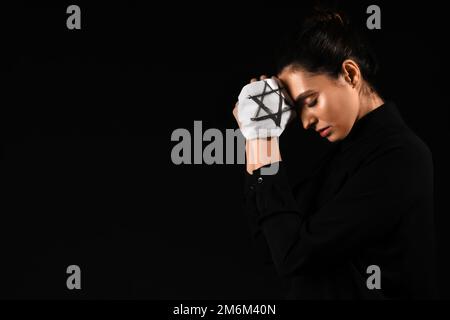 Young woman with armband praying on black background. International ...