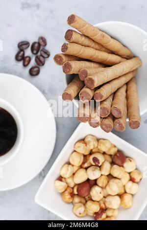 Delicious wafer rolls, nuts, coffee beans and chocolate on light table ...