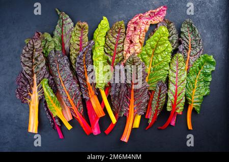 Raw colourful chard offered as a close-up on a rustic black board Stock ...