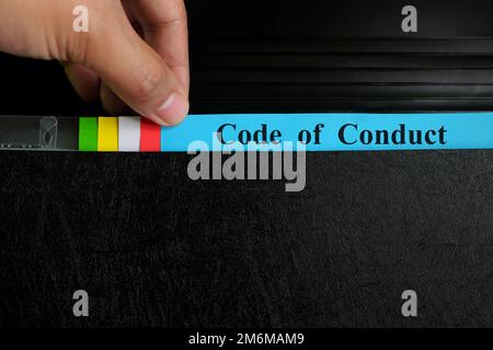 Hand picking code of conduct file record in black binder folder ...